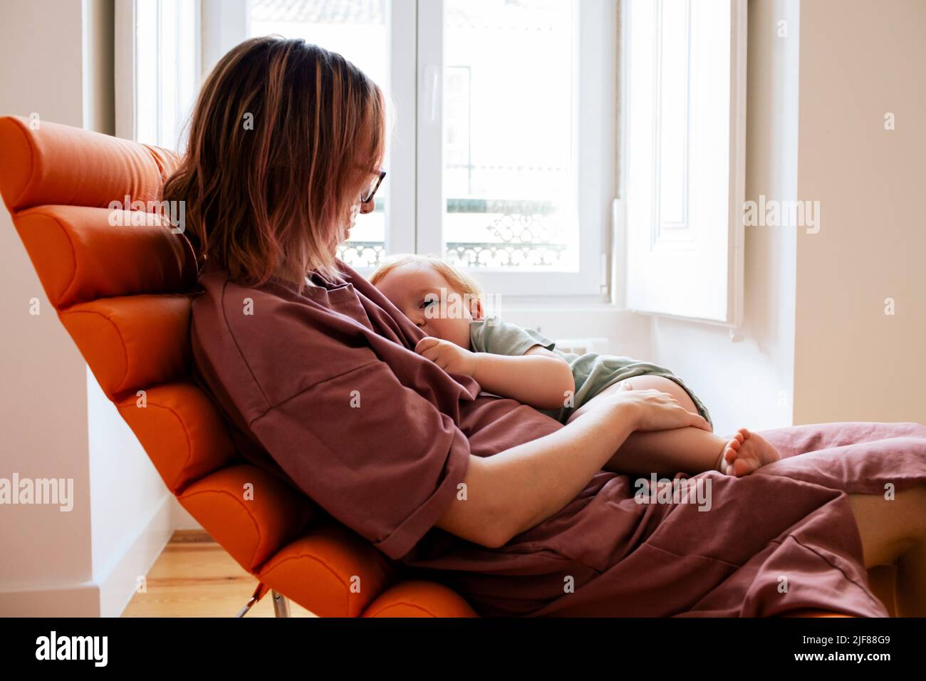 Mother with son sitting on chair at home Stock Photo - Alamy