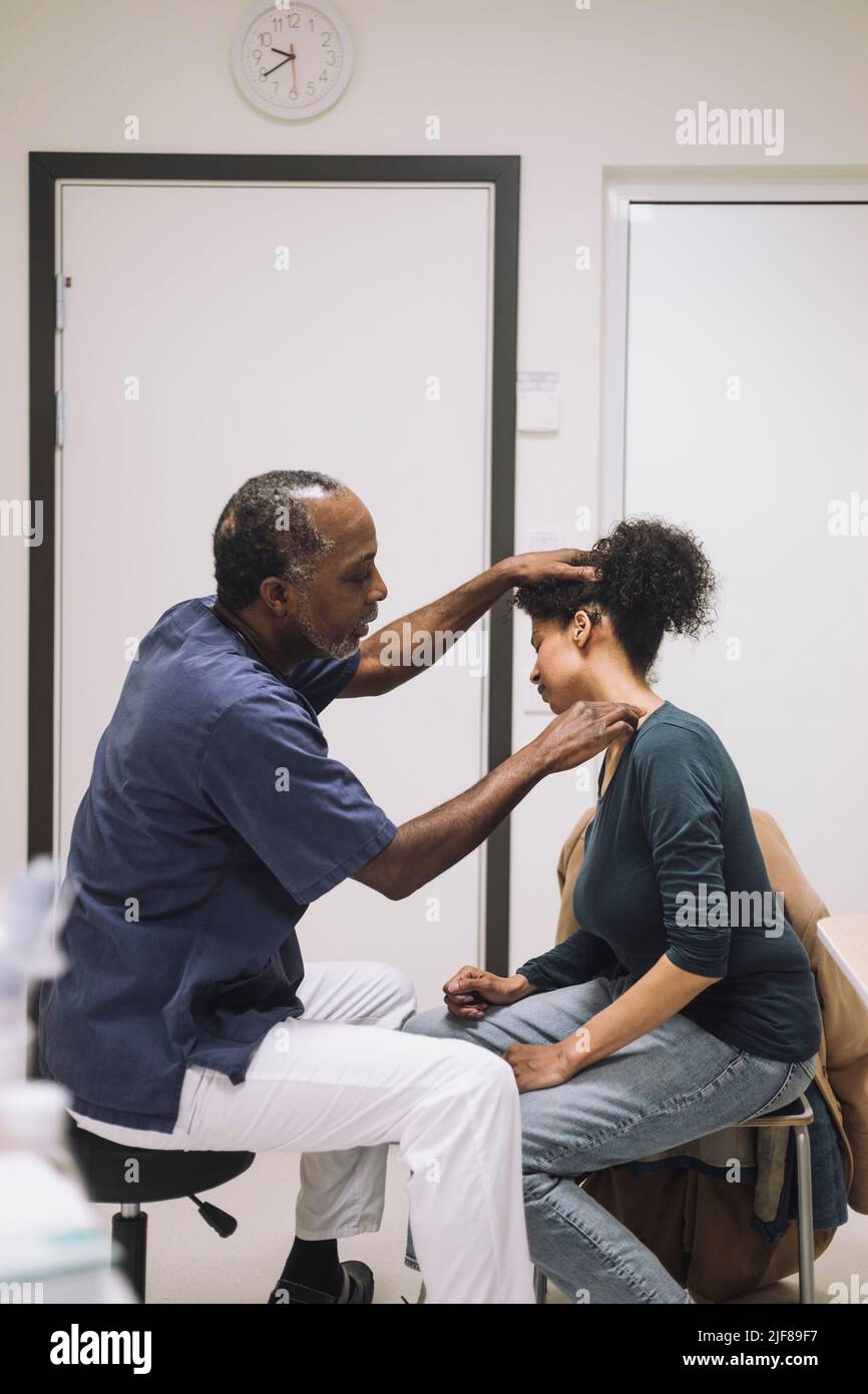 Side view of mature healthcare expert examining female patient in ...