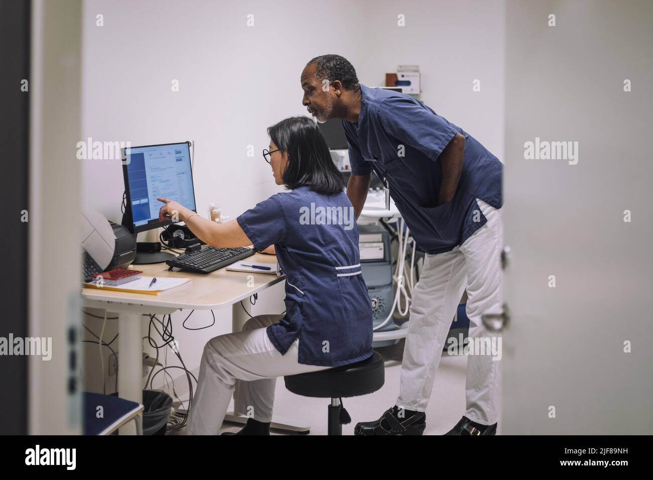 Female doctor pointing at computer monitor while discussing with male ...