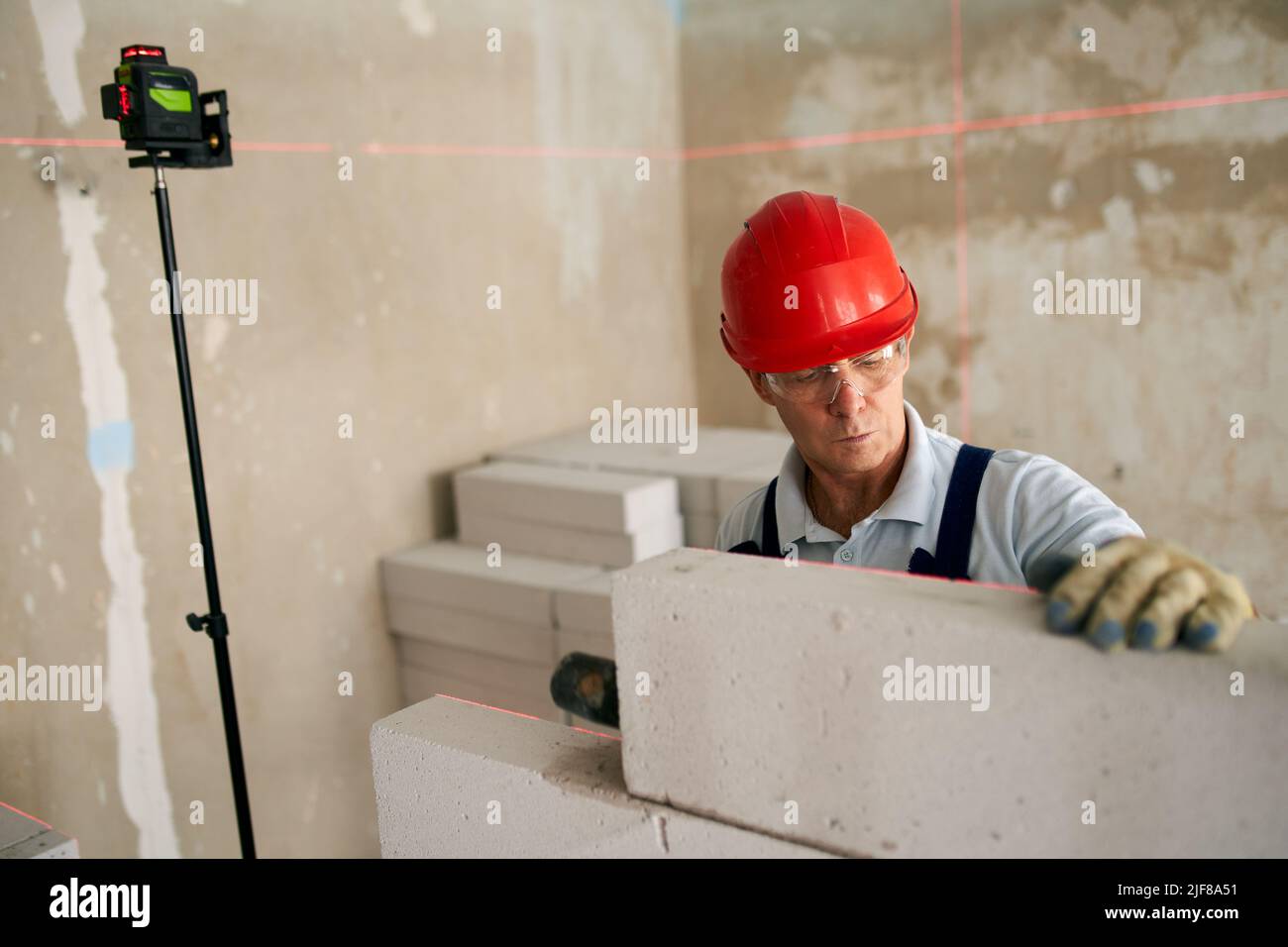 Bricklayer using rubber mallet hammer to tap and level concrete blocks ...