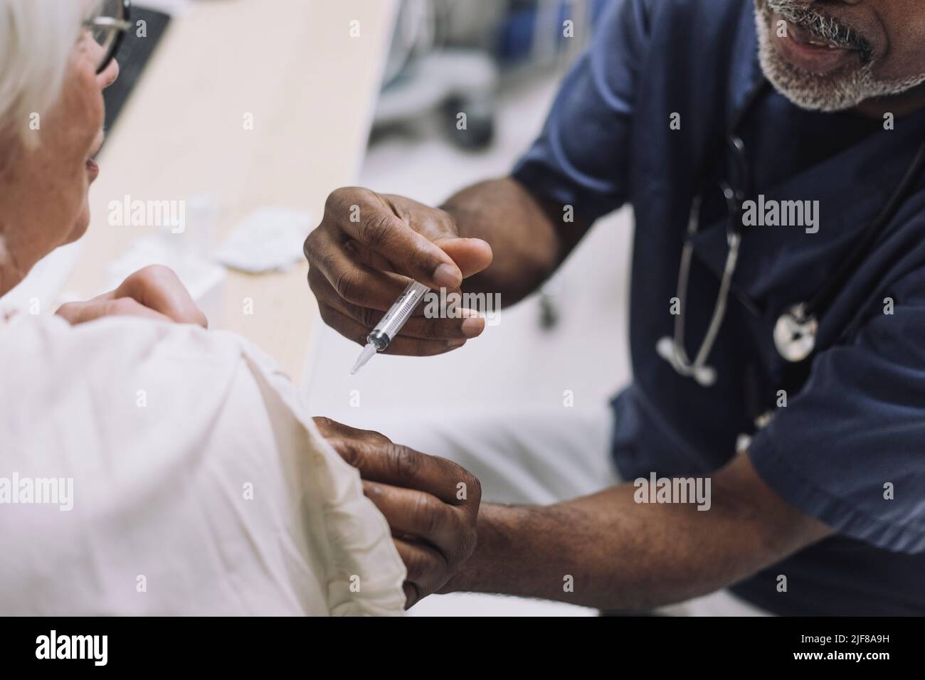 Male doctor injecting senior female patient in medical clinic Stock ...