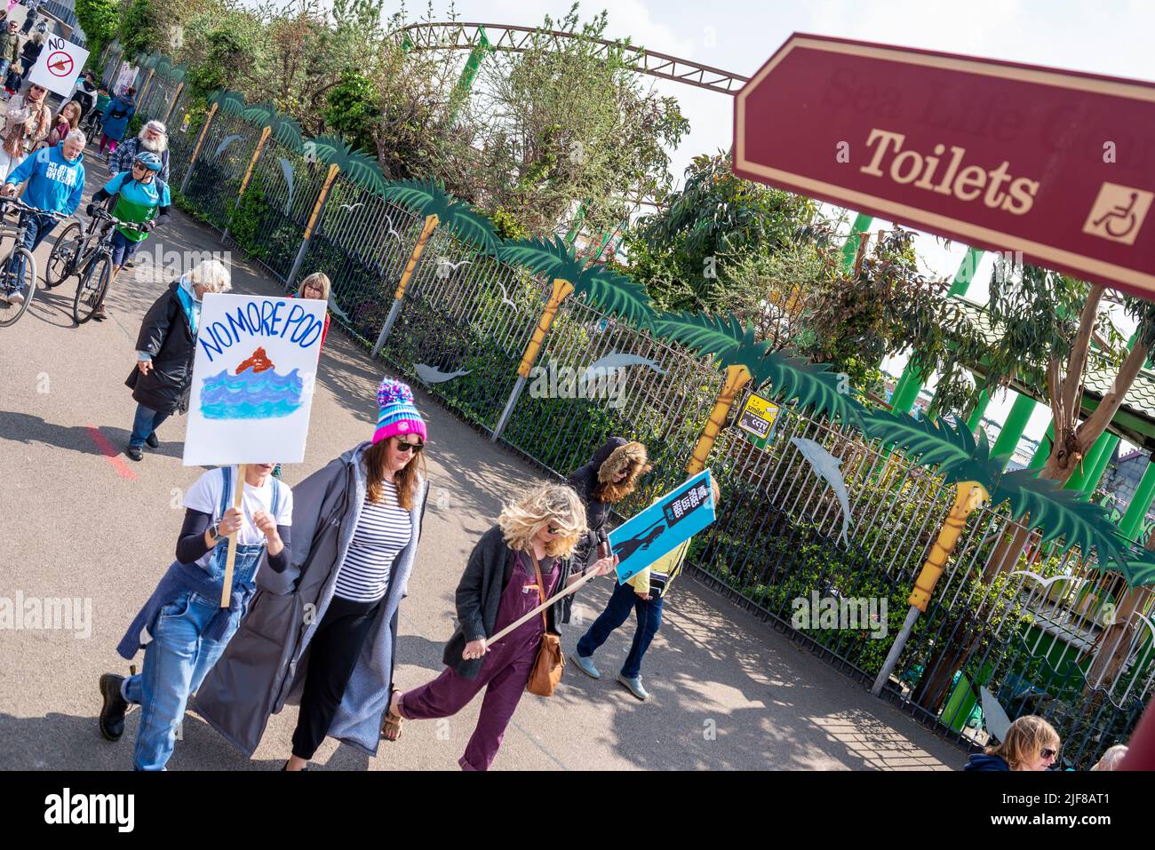 Protesters marching past toilet sign, with poo placard, whilst ...