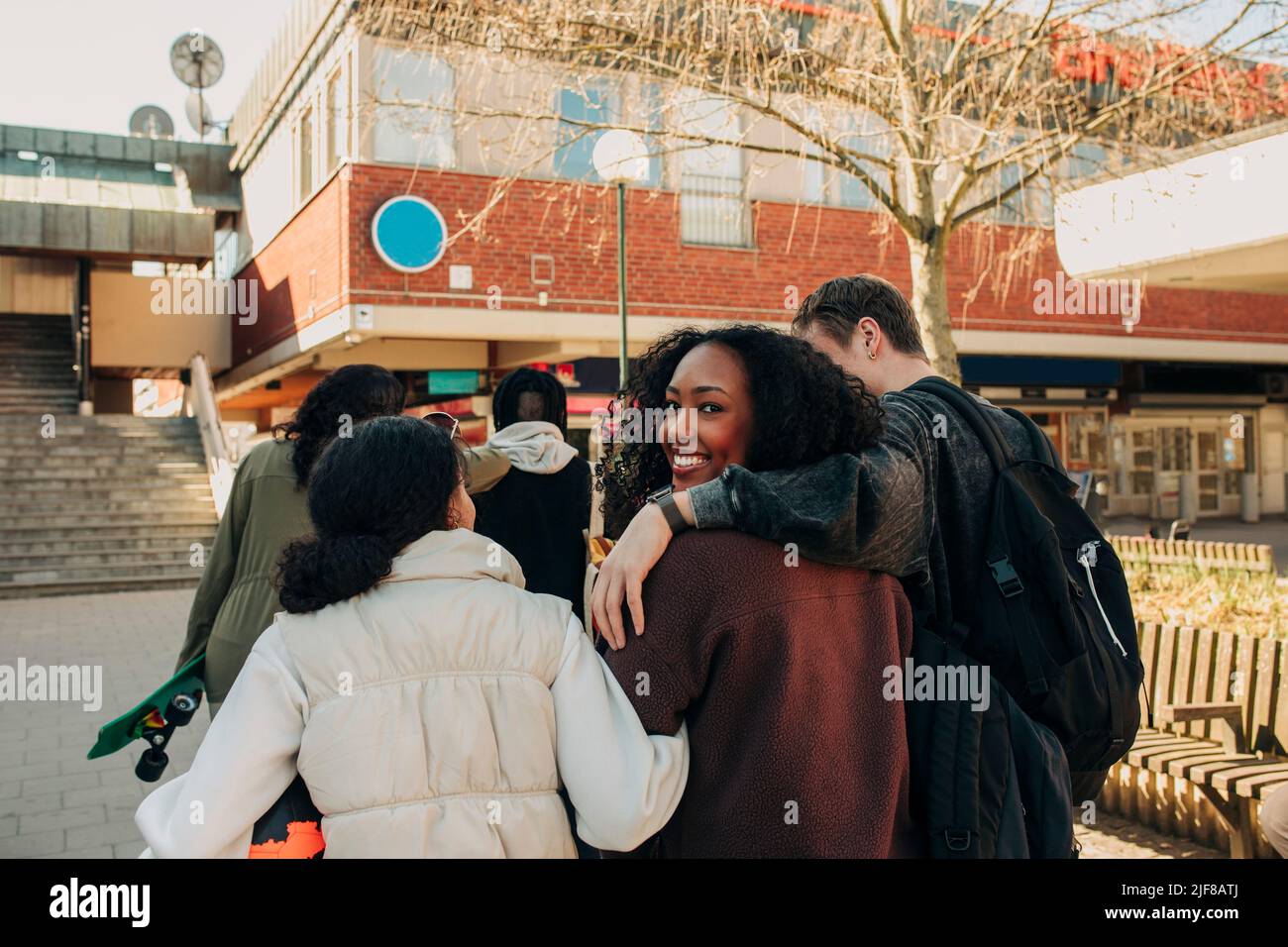 Rear view of smiling girl looking over shoulder while walking with ...