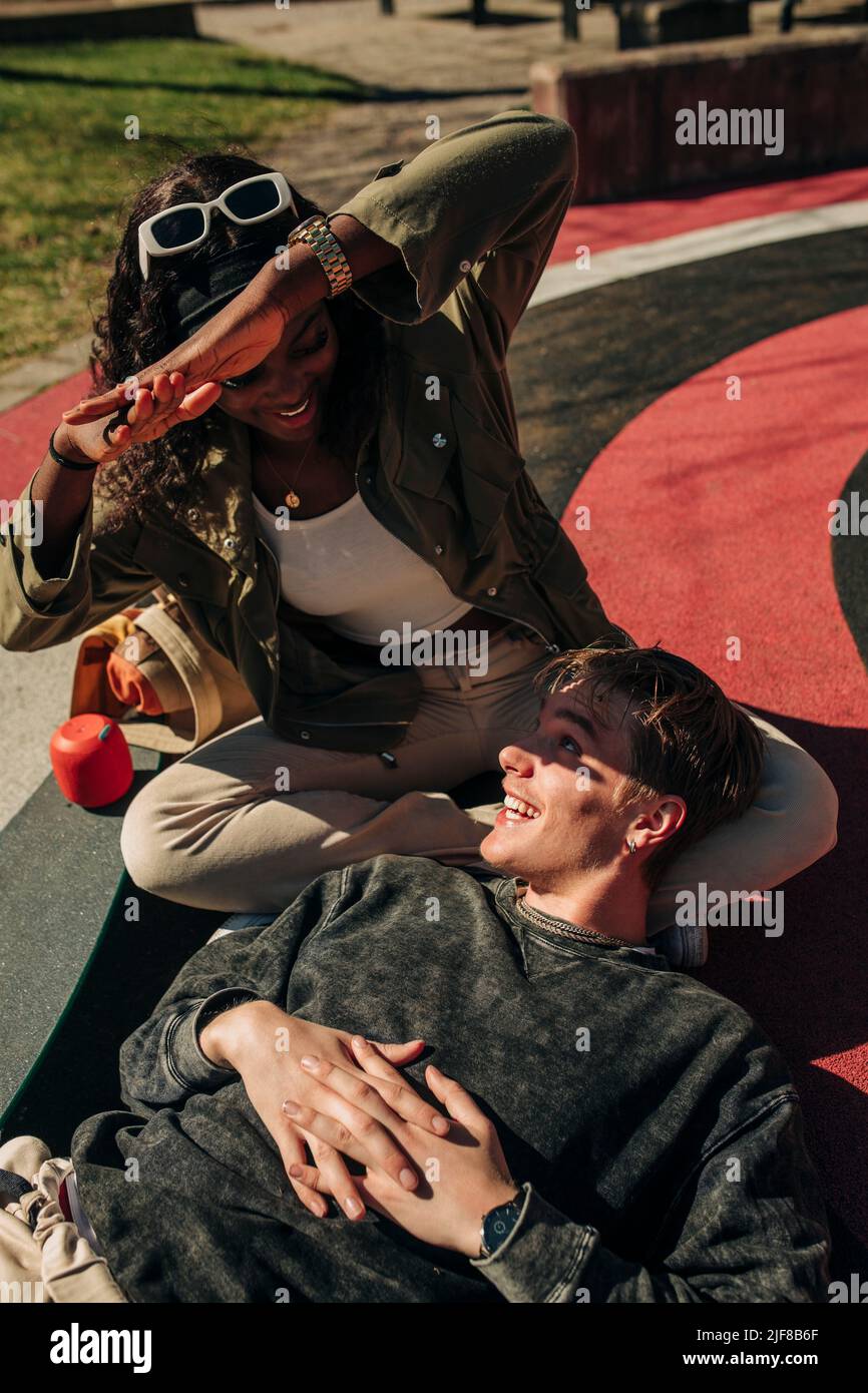 Woman protecting face of man from sunlight while lying in playground ...