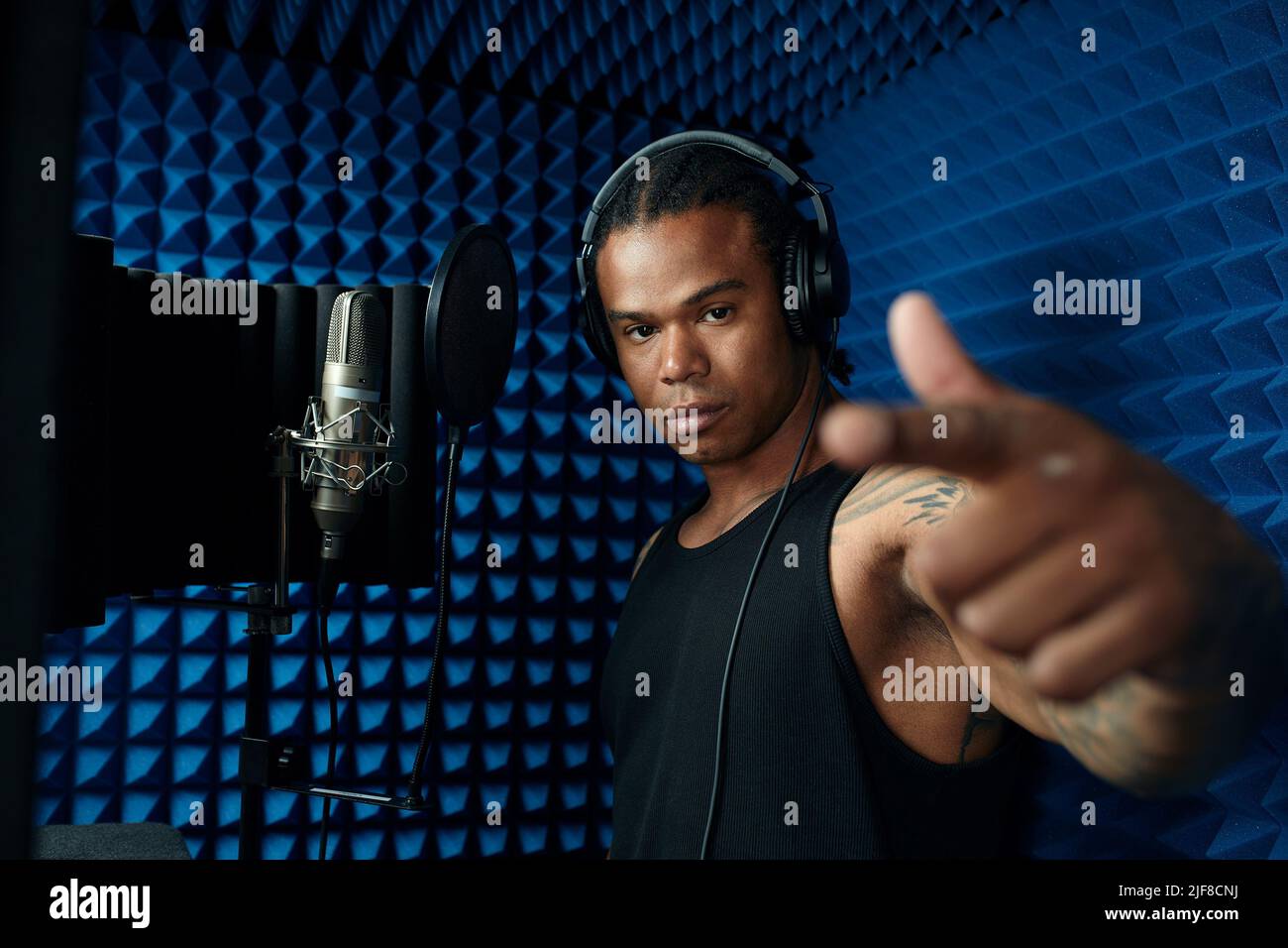 Close-up of handsome young Black singer standing in front of microphone ...