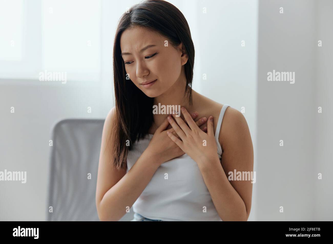 Heart attack. Suffering from pain tanned beautiful young Asian woman ...