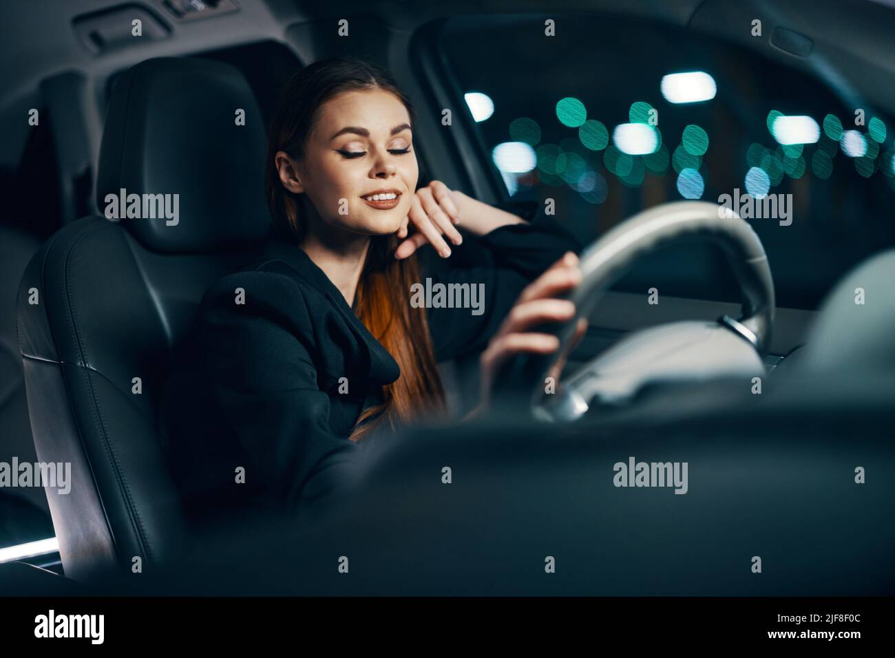 photo of a pleasant, relaxed woman sitting behind the wheel of a car ...