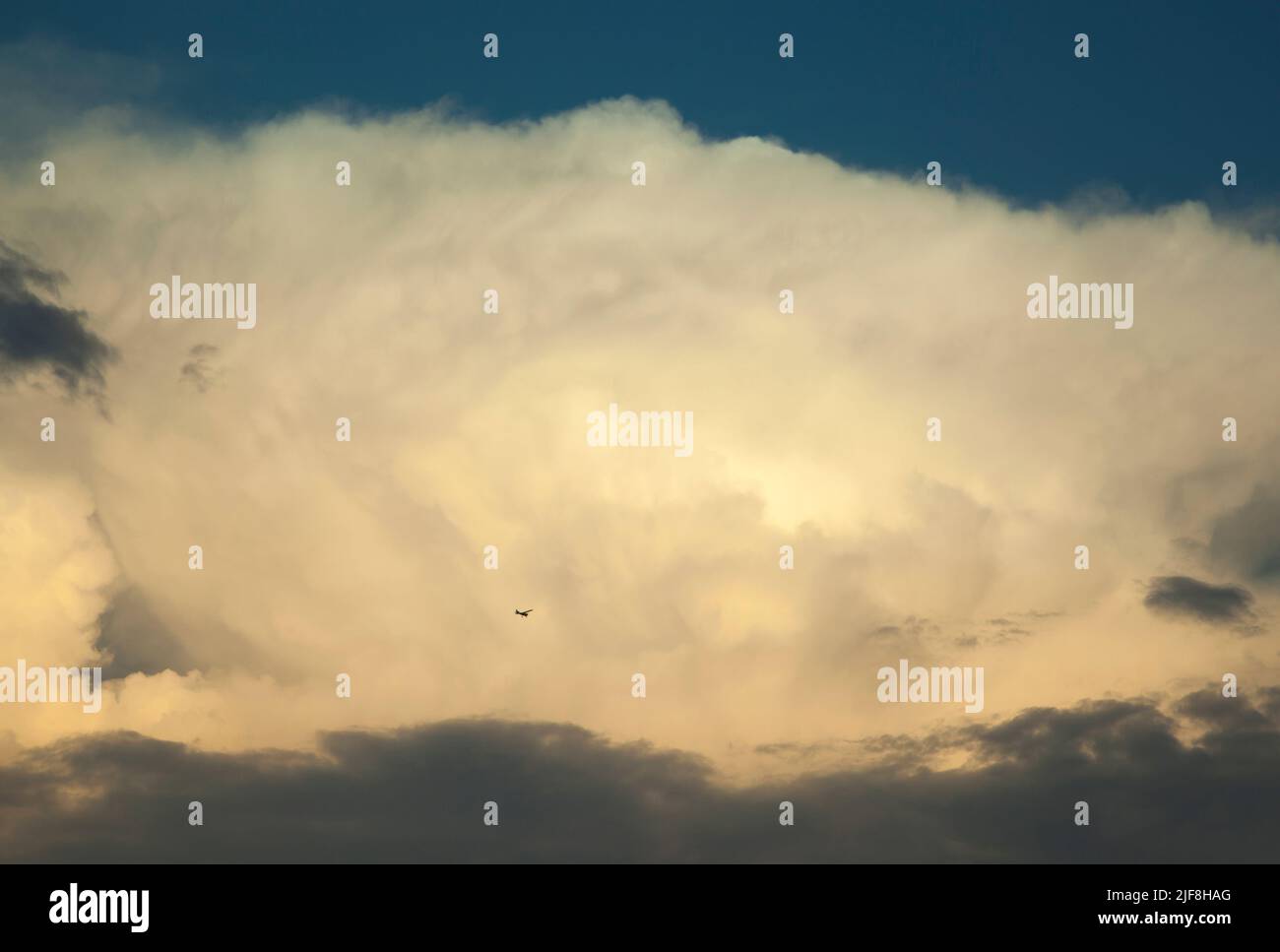 The small airplane passing through the brightly lit cloud by the sunset ...