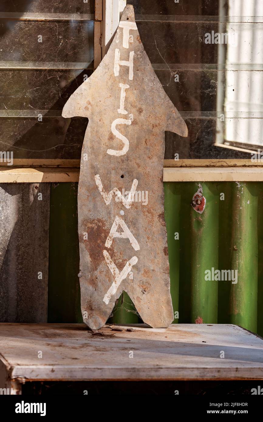 Old wooden arrow sign saying "This Way" propped against the wall of an ...