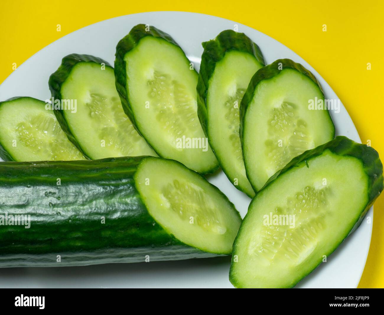 A smooth, medium-sized cucumber on a plate, sliced. Cucumber on a ...
