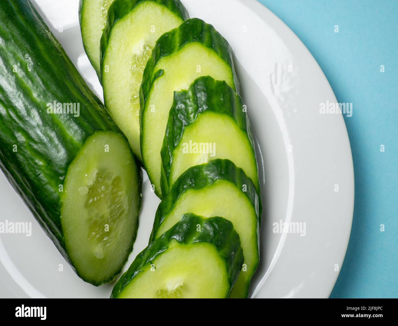 A smooth, medium-sized cucumber on a plate, sliced. Cucumber on a blue ...