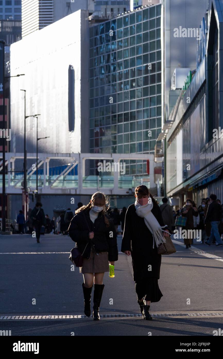 young Japanese women. wearing surgical masks, walking in the street ...
