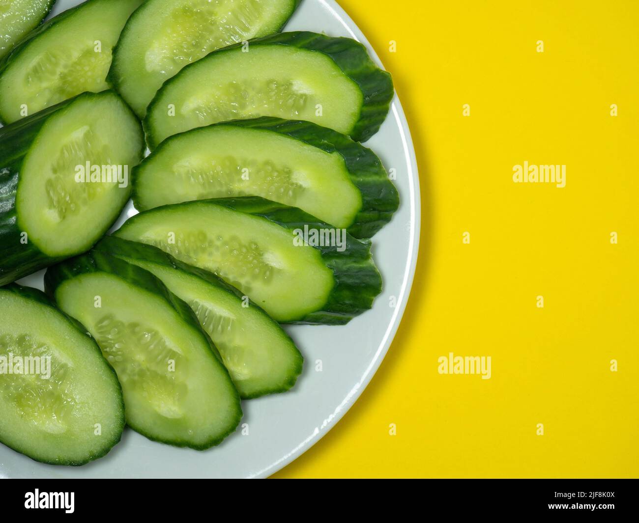 A smooth, medium-sized cucumber on white plate, sliced. Cucumber on a ...