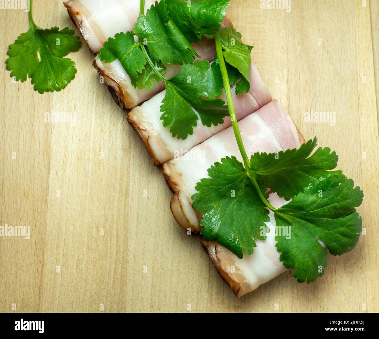 Curvy cut folded into rolls. Pork on a kitchen board with parsley ...