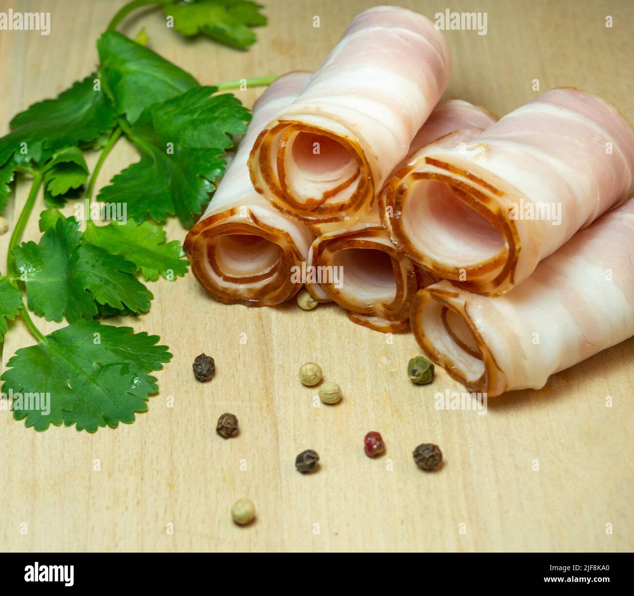Curvy cut folded into rolls. Pork on a kitchen board with parsley ...