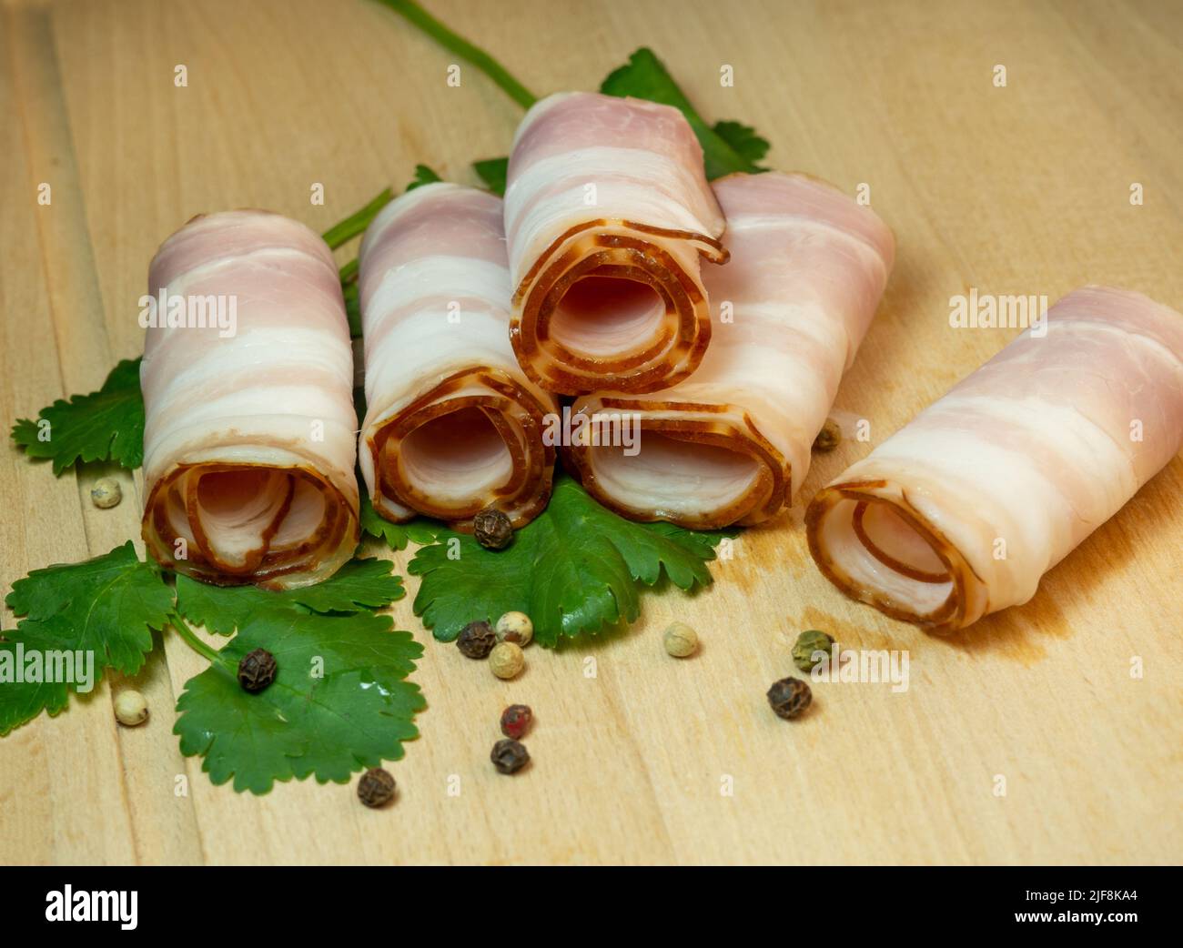 Curvy cut folded into rolls. Pork on a kitchen board with parsley ...