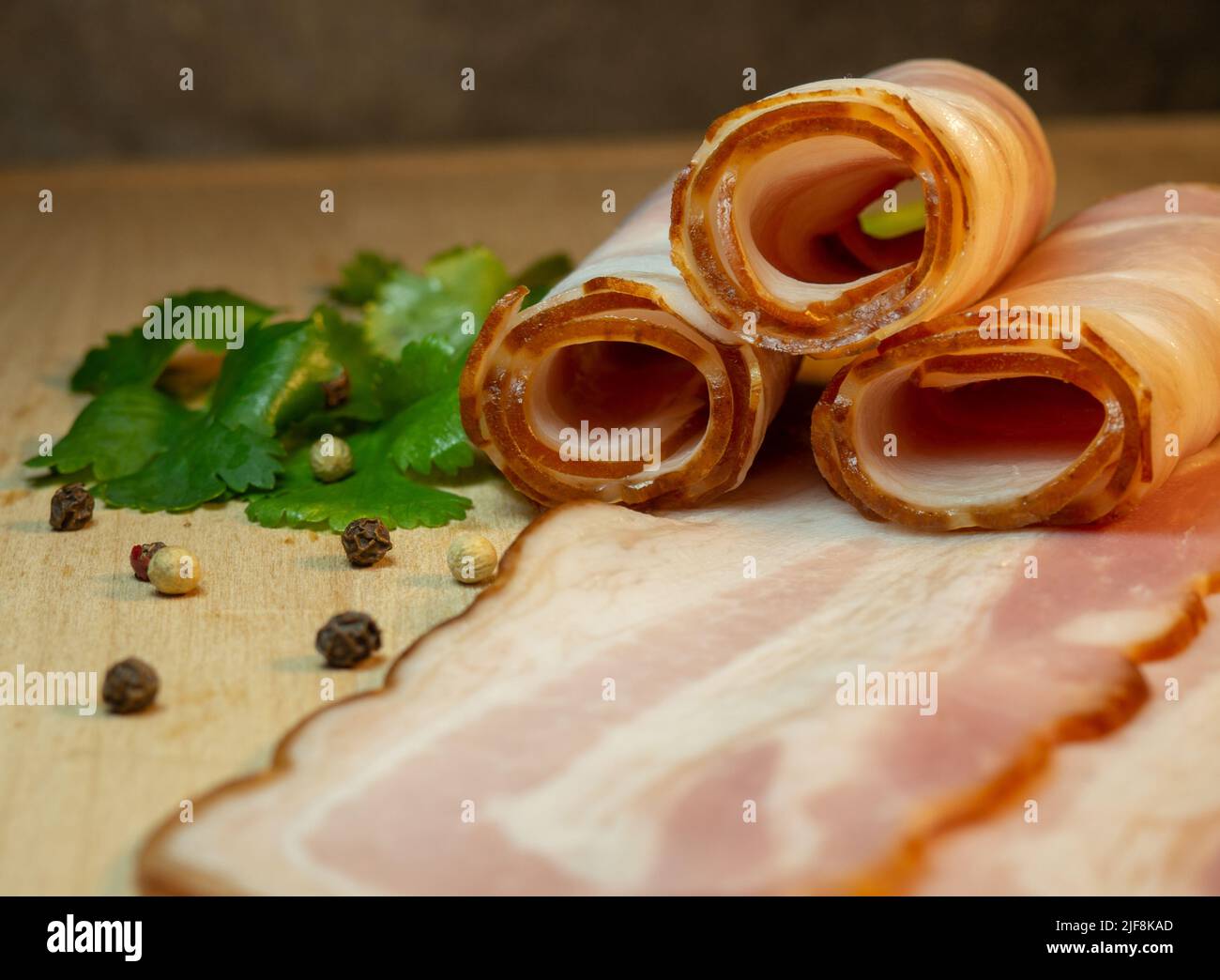 Curvy cut folded into rolls. Pork on a kitchen board with parsley ...