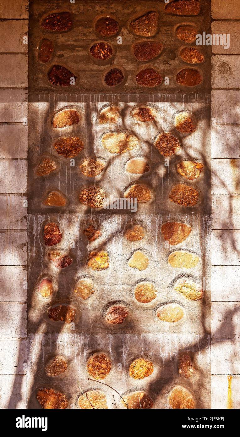 An old concrete block wall with a stone pitched panel of facade ...