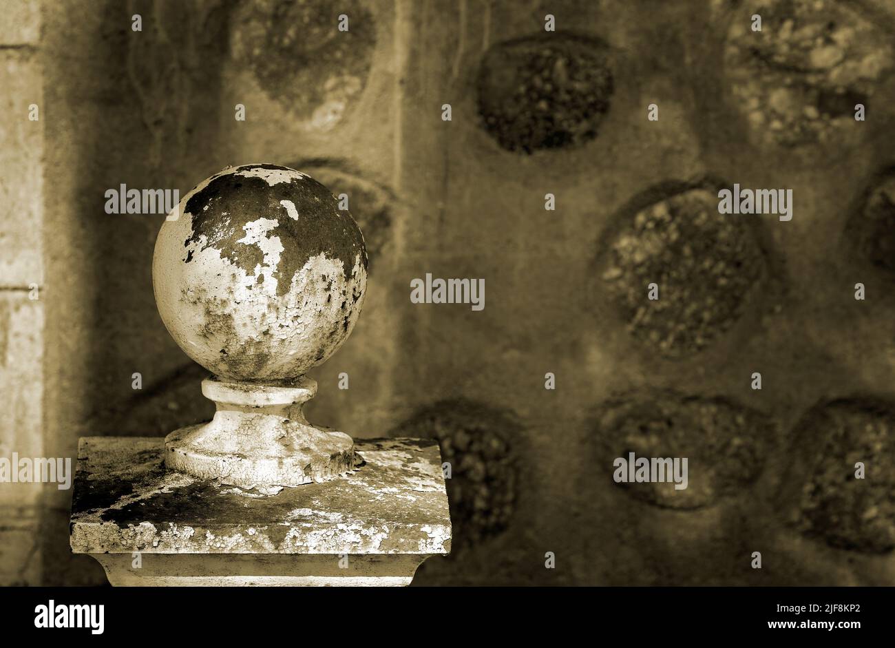 An old round concrete globe statue pitted with age, situated at the ...