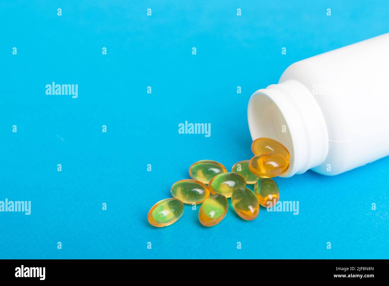 Omega-3 capsules lie in white bottle on a table background. Fish oil ...