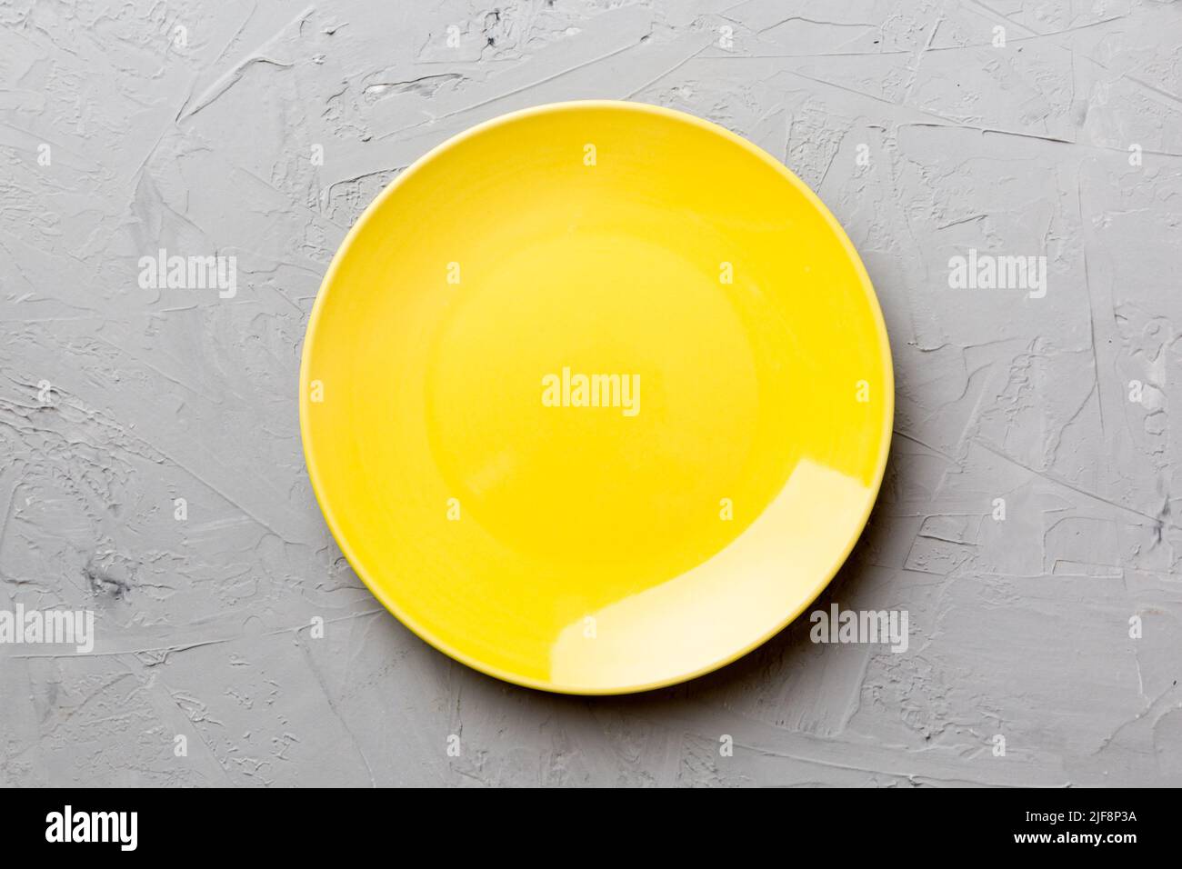 Top view of empty yellow plate on cement background. Empty space for ...