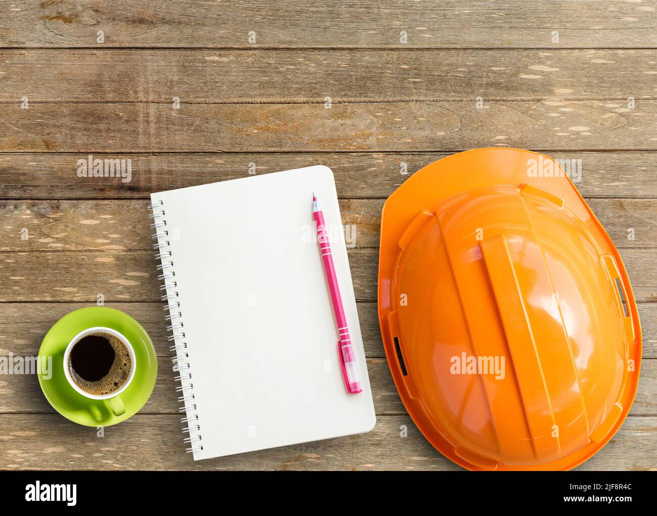 Orange Safety helmet,coffee cup and notebook with pen on wood table in ...