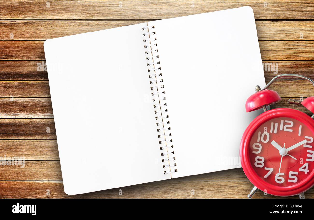 Top view with paper notepad,red alarm clock and coffee cup on wood ...