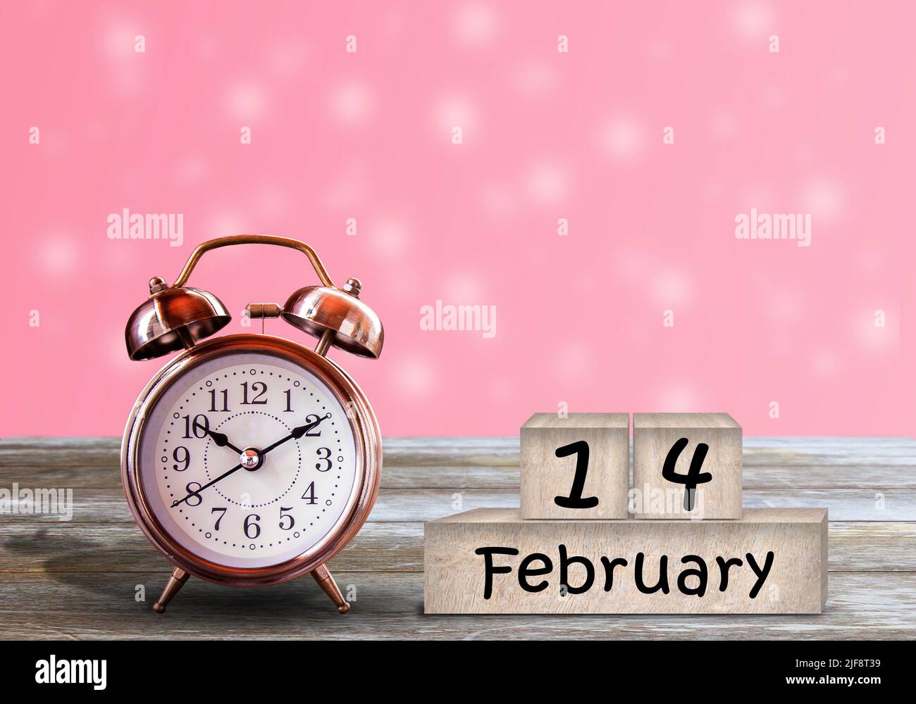 Vintage alarm clock and text 14 february on wood block with pink bokeh ...