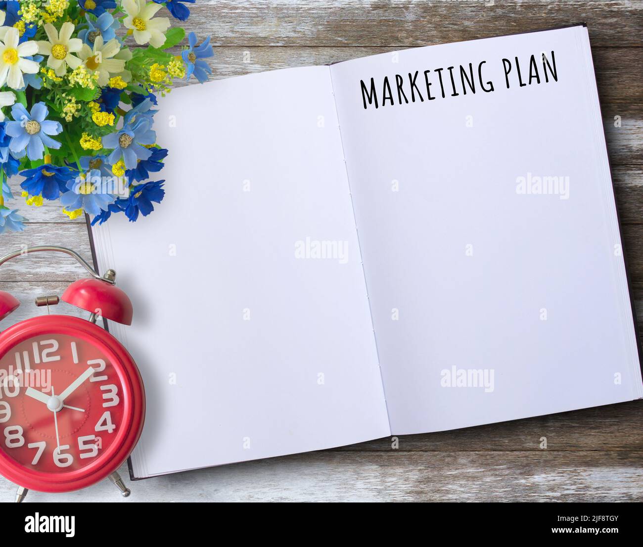 MARKETING PLAN text on notebook with flower and retro red alarm clock ...