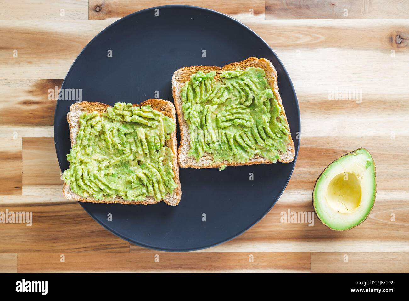 basic plant-based smashed avocado toast with half avocado next to it ...