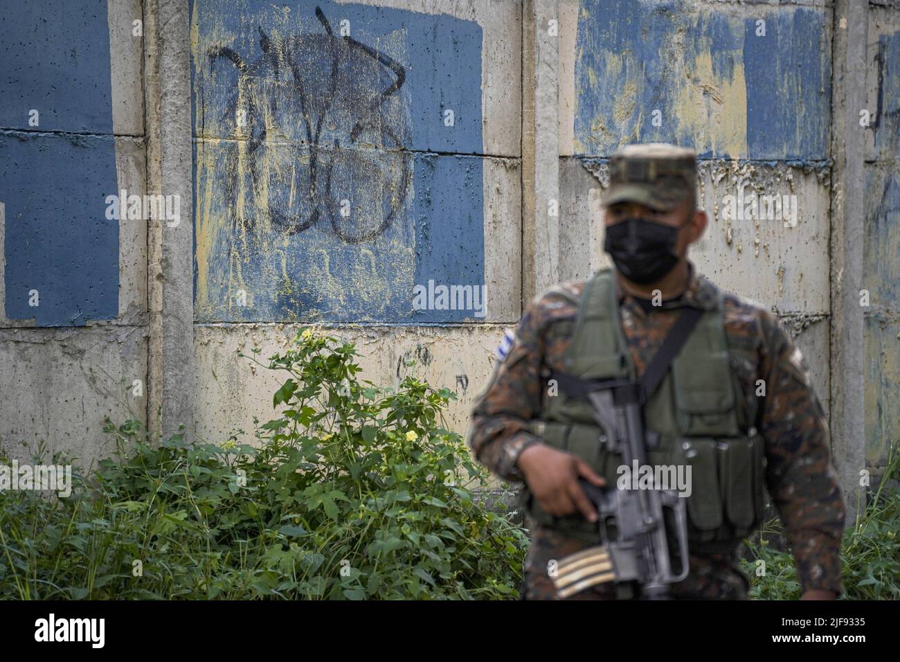 A soldier stands next to an errand graffiti from the Barrio 18 Sureños ...