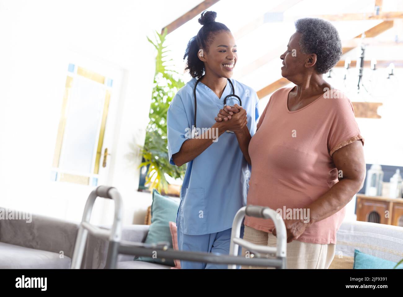 Smiling african american doctor holding senior patient's hand while ...