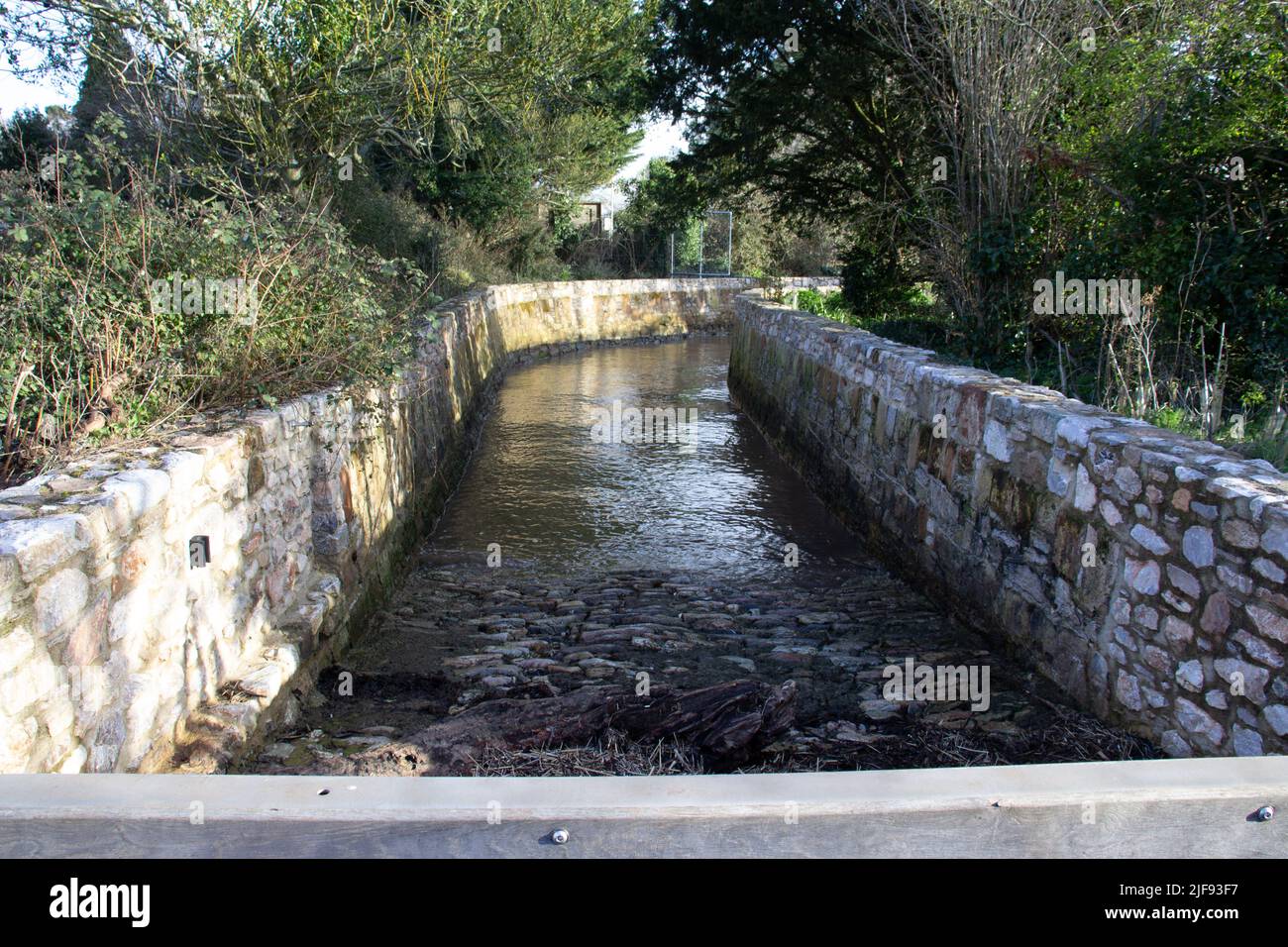 flood defence with rock walls and trees on the side and sea water ...