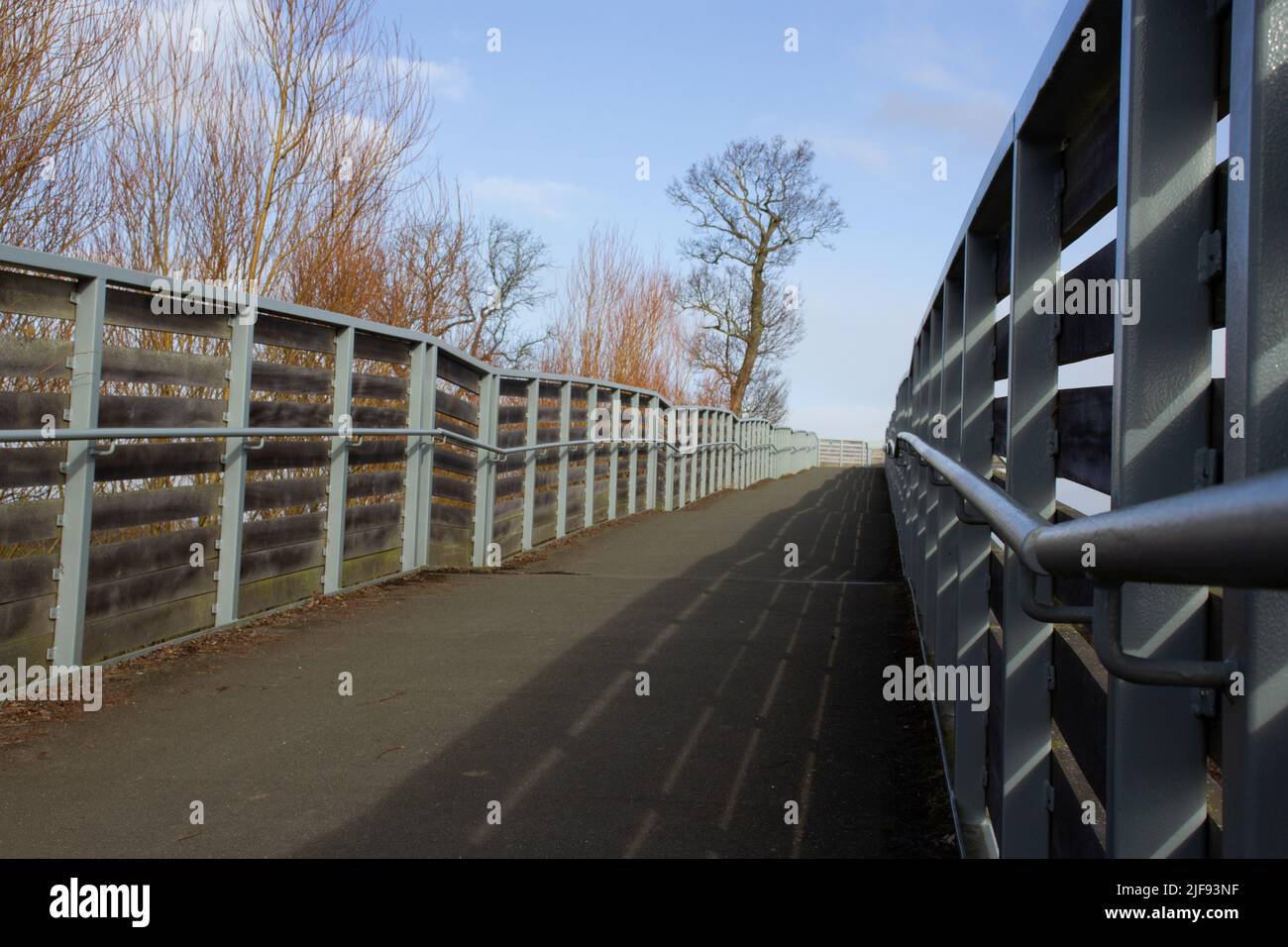 shared-use path up to a bridge over with winter trees and a blue sky ...