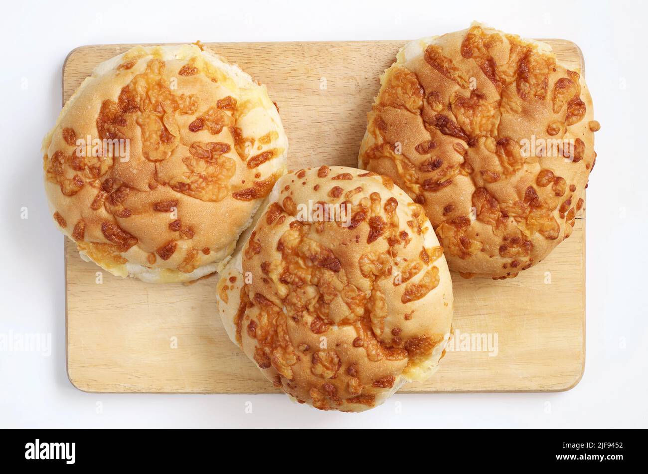 Three cheese bread rolls on a cutting board on a white background close ...