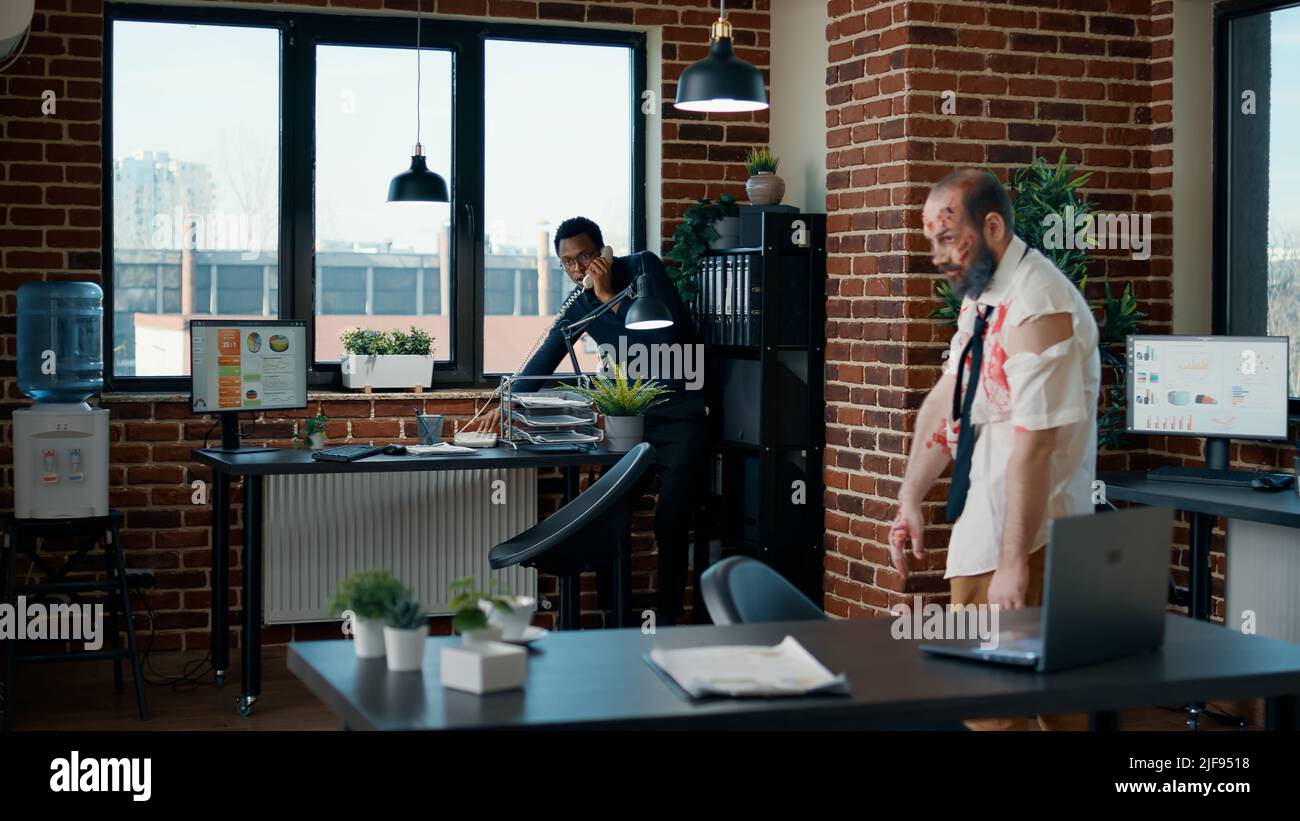 Scared businessman calling emergency while running from scary bloody ...