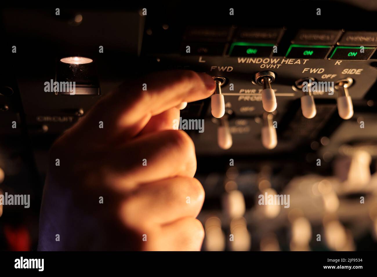 Plane captain pushing power switch on dashboard panel in cabin to ...