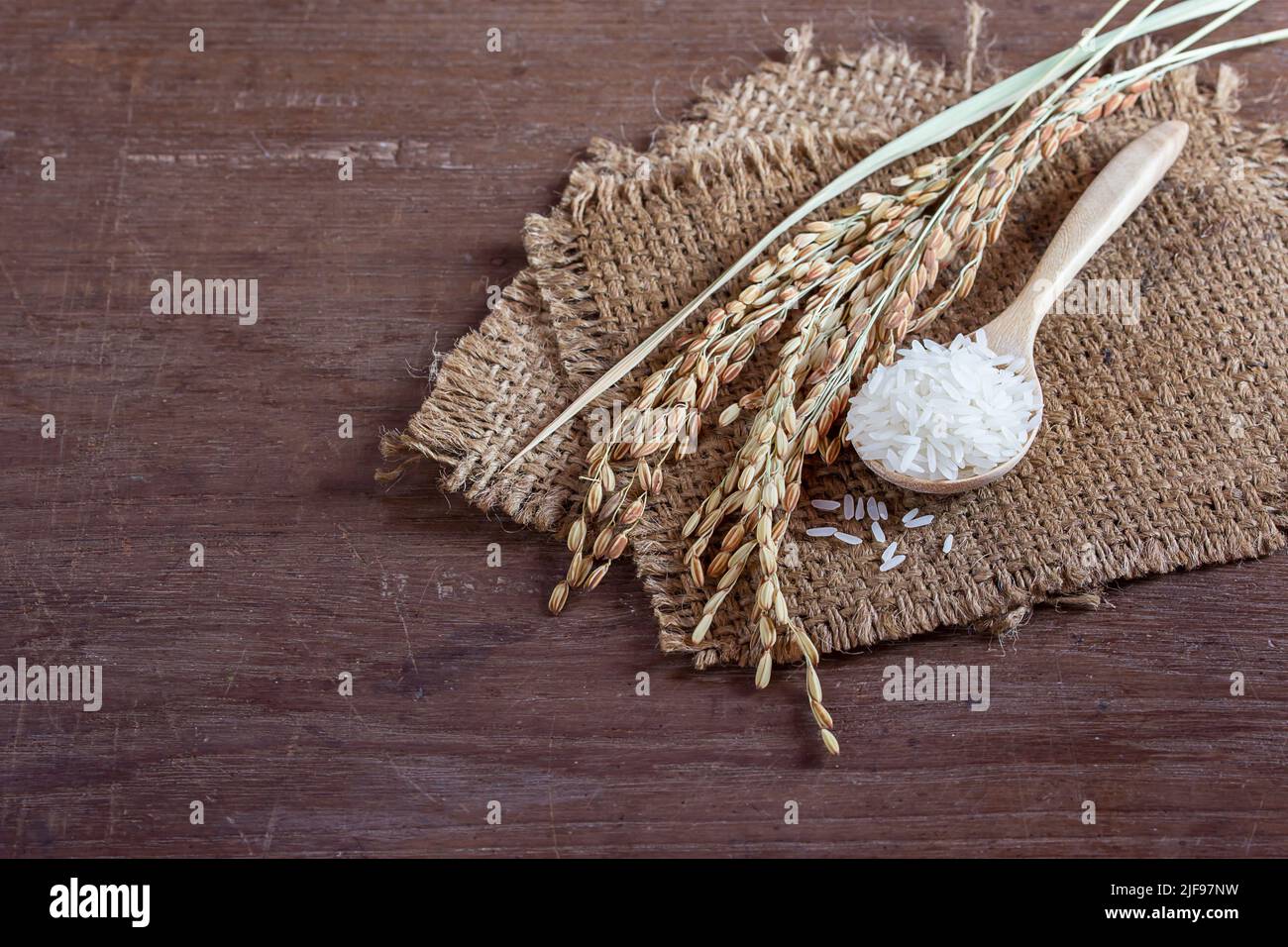 Thai jasmine rice, uncooked rice in wood spoon on wooden background ...