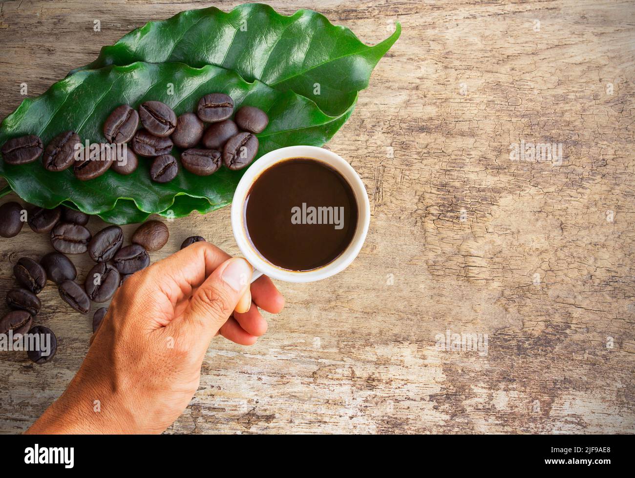 Business man holding a cup of coffee with coffee beans on wooden table ...