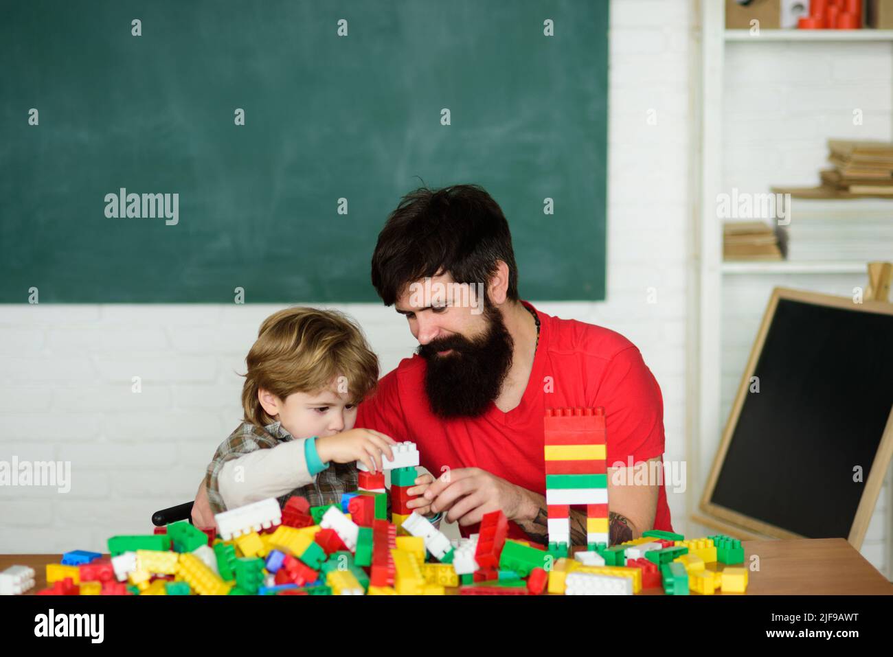 Father and son create toys from bricks. Dad and kid build of plastic ...