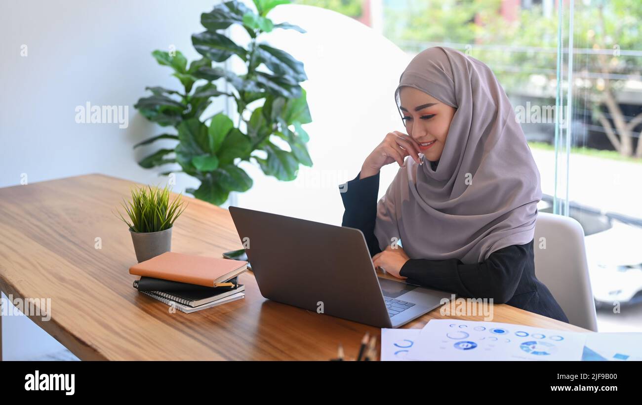 Asian muslim businesswoman manager in hijab using laptop and working ...