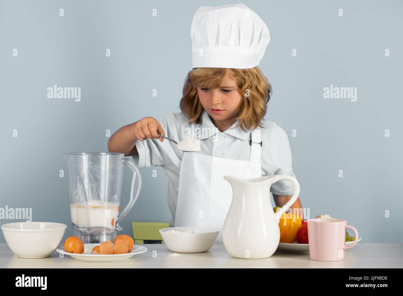 Kid boy in chef hat and apron cooking preparing meal. Little cook with ...