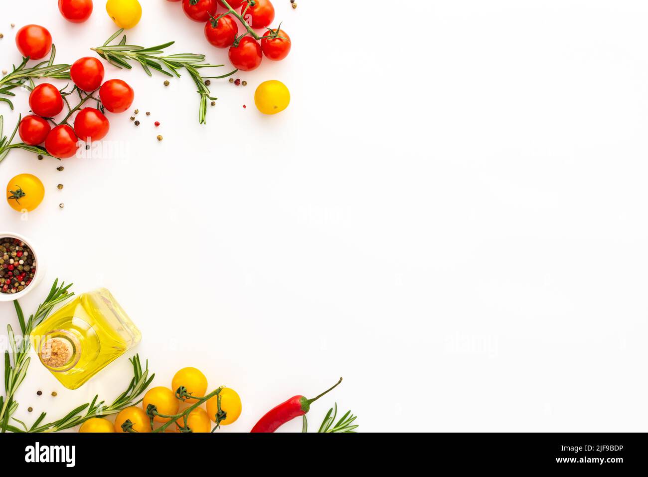 Yellow and red tomatoes, hot peppers, rosemary and spices on a white ...
