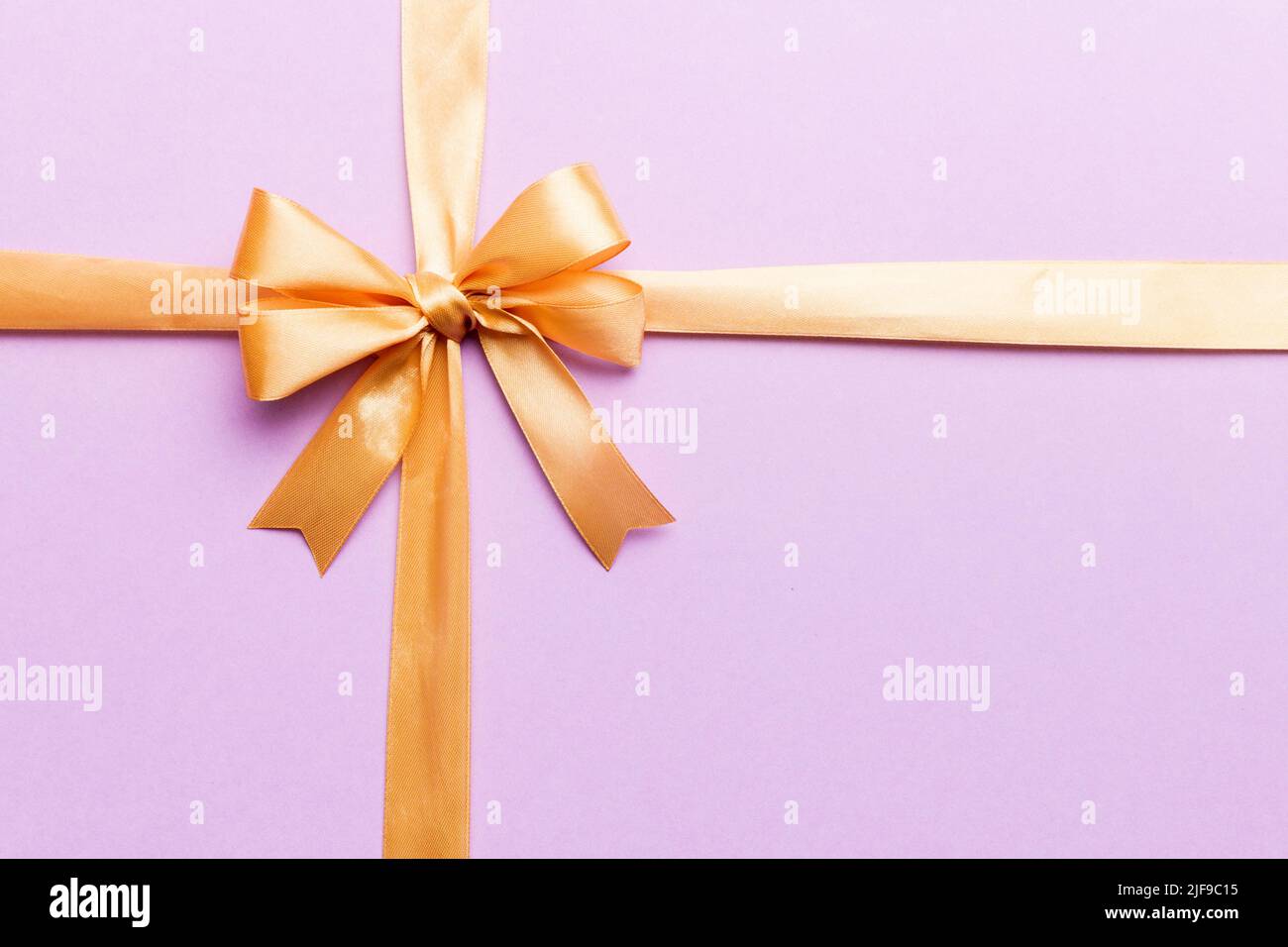 Top view of gold ribbon rolled and yellowbow isolated on colored ...