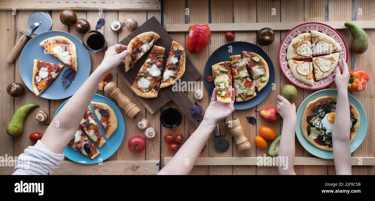 Girl and women hands take a slices of pizza overhead view Stock Photo ...