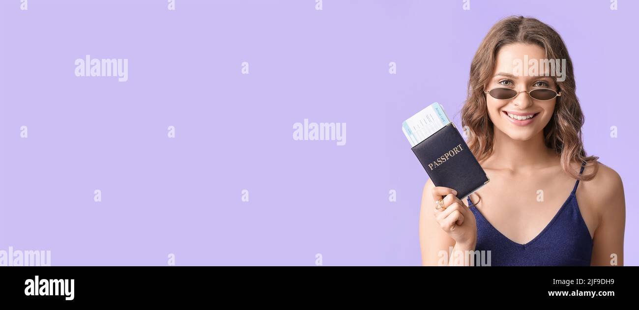 Beautiful female tourist holding passport and tickets on lilac ...