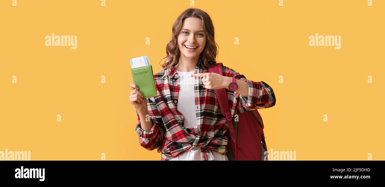 Beautiful female tourist with passport and tickets on yellow background ...