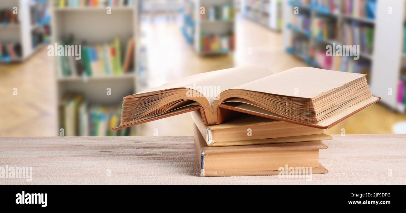 Stack of books on table in modern library Stock Photo - Alamy