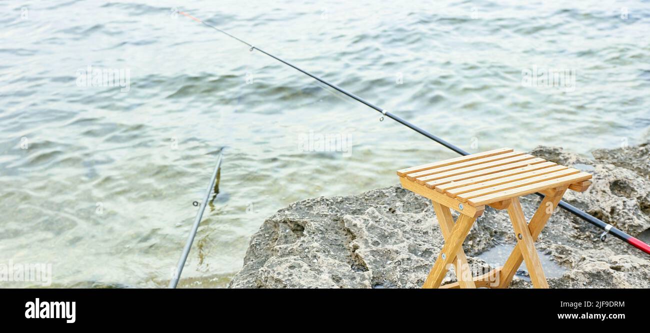 Stool and fishing rod on river bank Stock Photo - Alamy