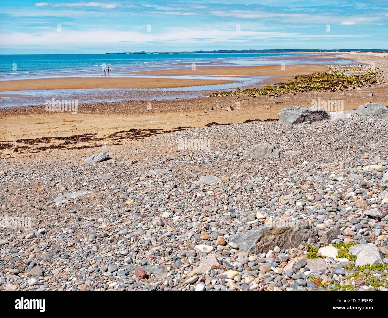 two figures on Dinas Dinlle beach near Caernarfon North Wales with ...